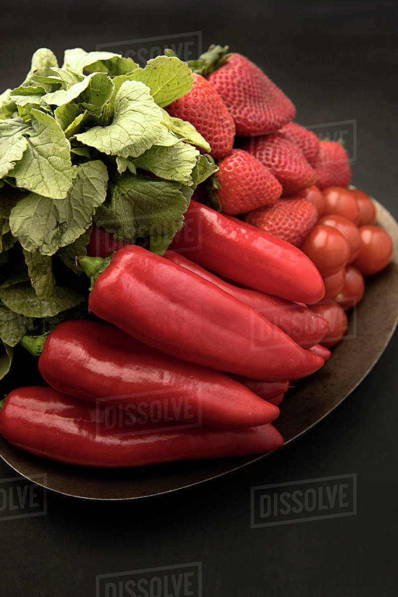 An assortment of red fruits and vegetables on a platter consisting of ...