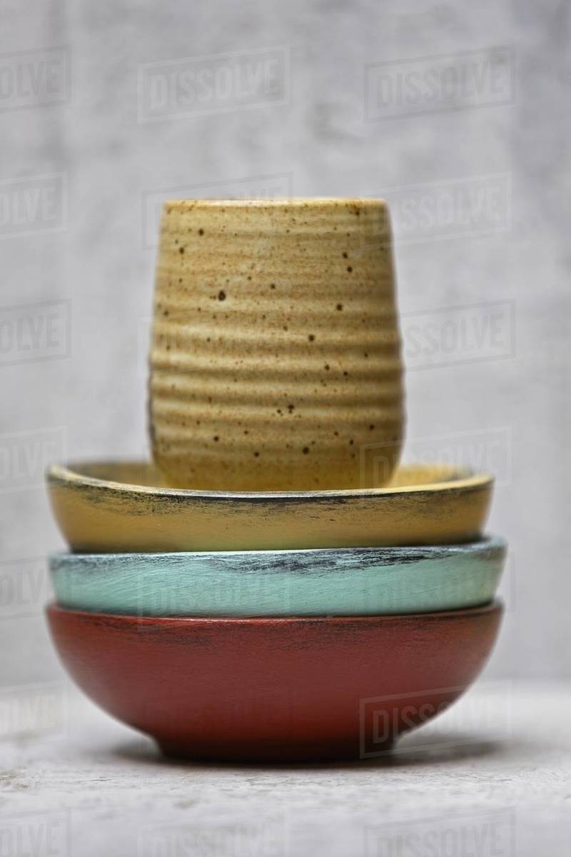 A close up photo of multi colored bowls and a homemade cup stacked ...