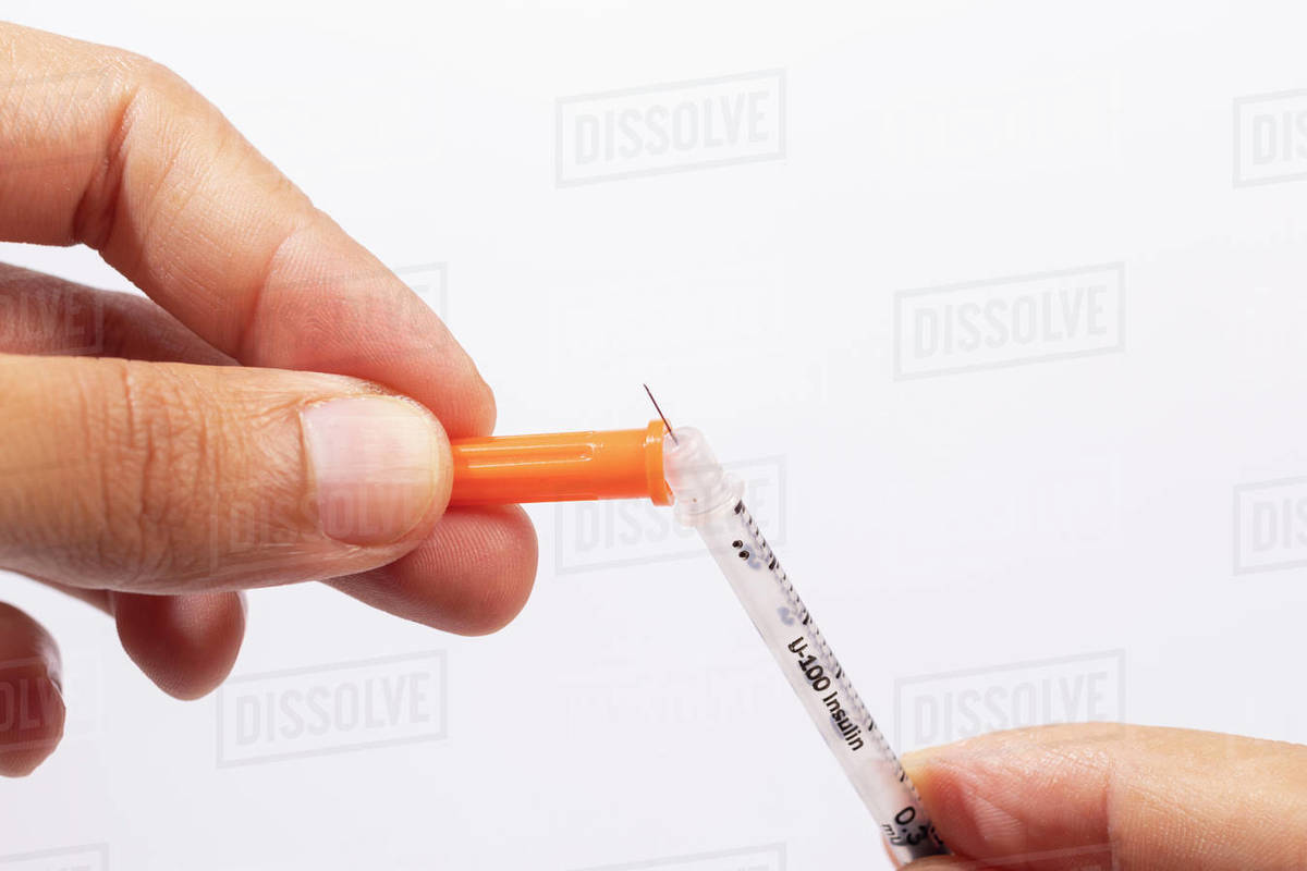 Hand holding an insulin syringe before being used - Stock Photo - Dissolve