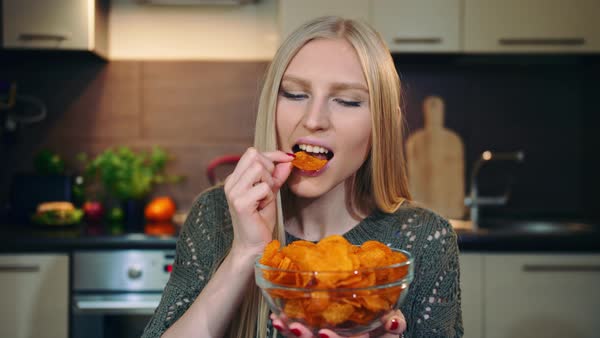 Glad woman eating potato chips. Beautiful young female enjoying potato ...