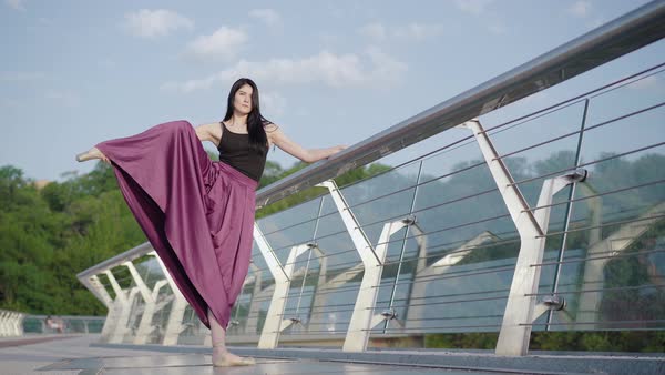 Wide shot of beautiful ballerina holding bridge handrail and raising ...