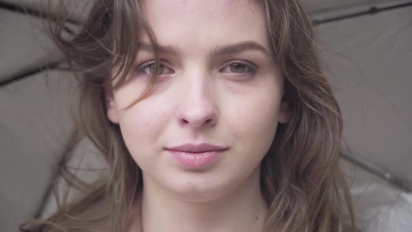 Close-up face of gorgeous sad woman crying outdoors on rainy windy day ...