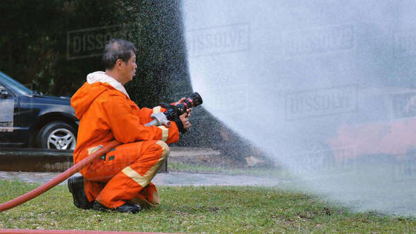 Firefighter fighting with flame using fire hose chemical water foam ...