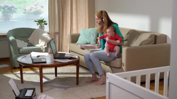 Young mother with baby working from home. A freelance single mom with ...
