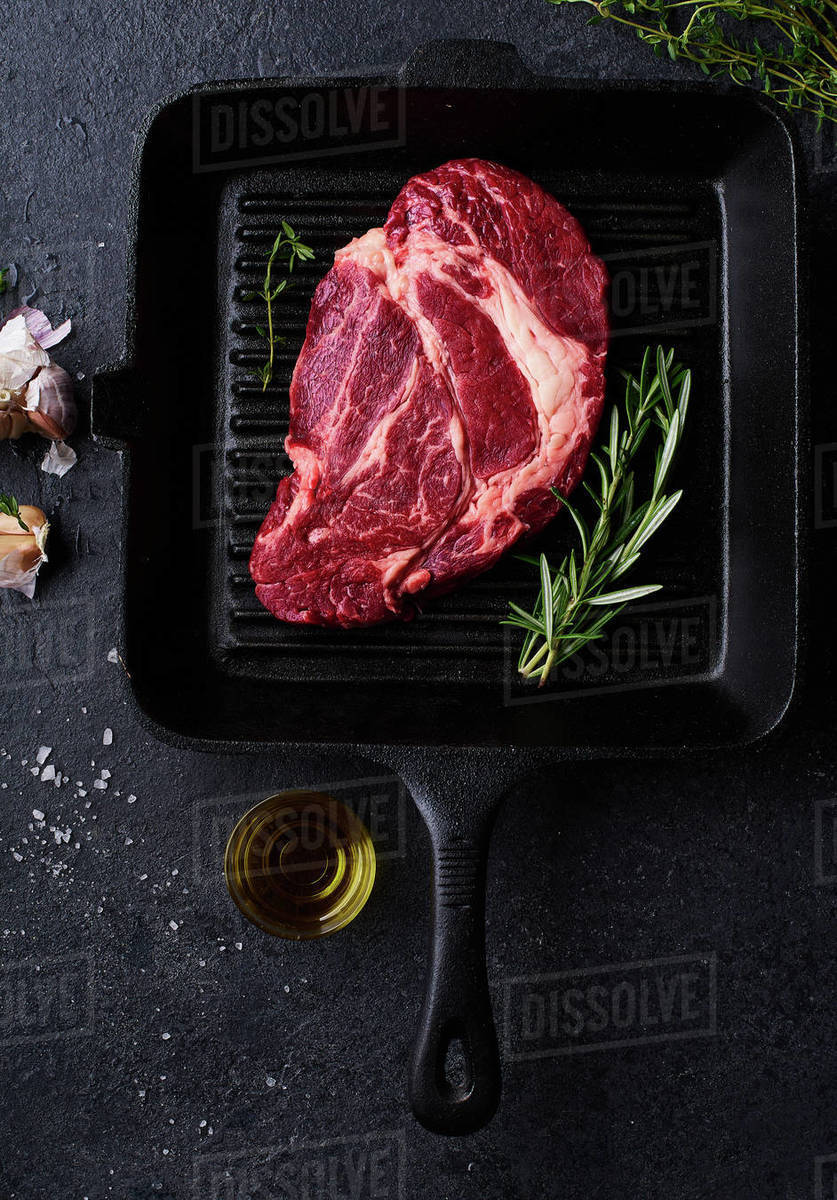 Top view Black Angus prime beef chuck roll steak on cast iron grill pan ...