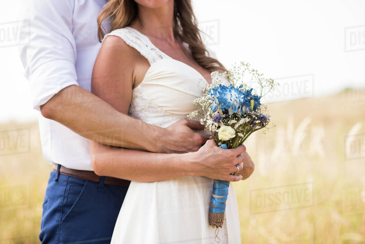The groom hands the bride hugging on the background fields, and the ...
