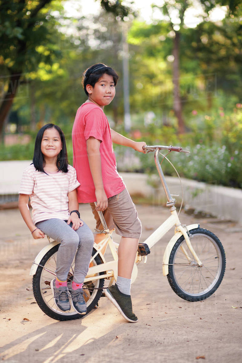 Brother and sister ride a bicycle in public park - Royalty-free Stock ...
