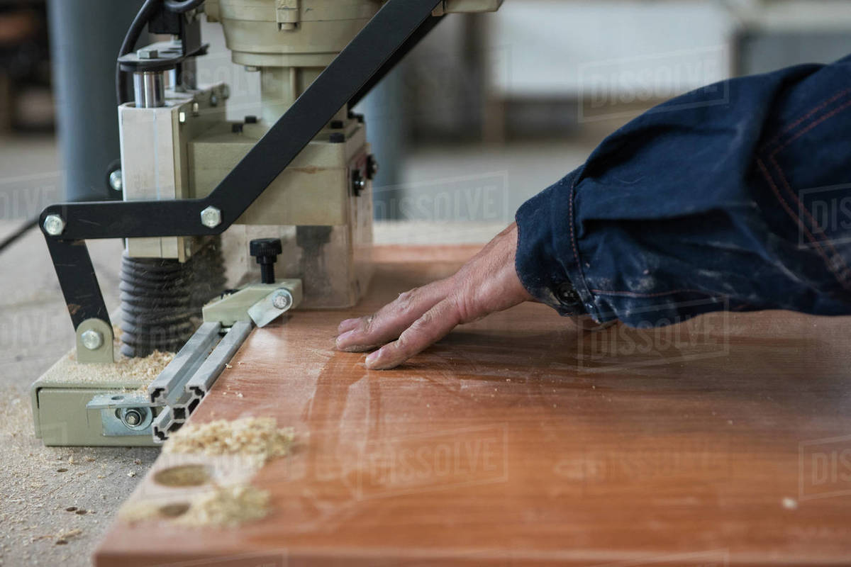 Furniture production concept: man working at machine and making ...