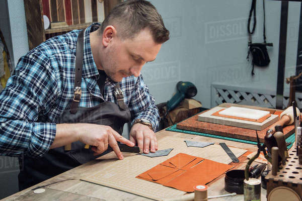 Man working with leather textile at a workshop. Craftman cutting ...