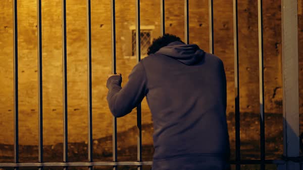 Symbol of suffering - young man is desperate grabbing the bars of the ...