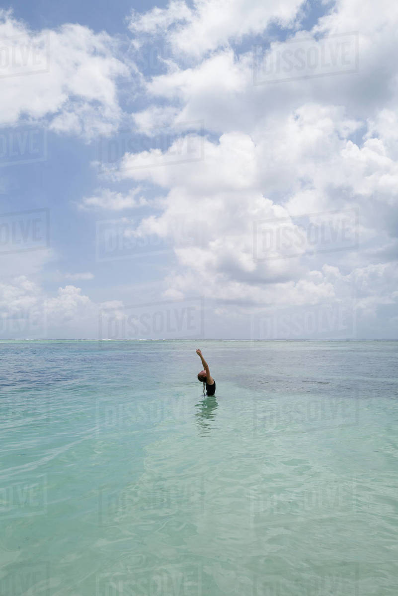 Woman standing in the water with her arms raised up to the sky - Stock ...