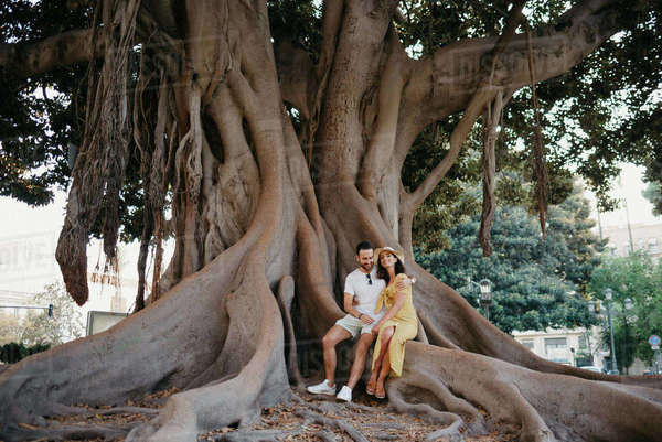 A young woman in a hat and a yellow dress hugs with her boyfriend with ...