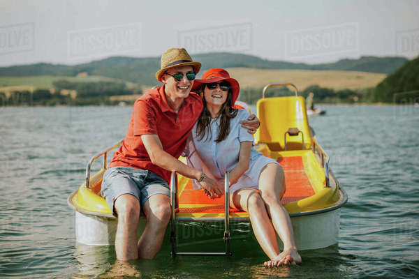 Front view of smiling young couple sitting on pedal boat. Portrait of ...