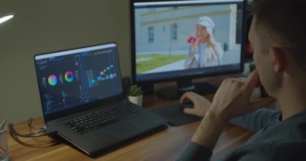 Man working on computer with Two Monitors Color Correction Post ...