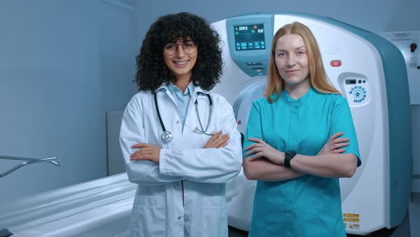 Two MRI specialists posing with arms crossed. Doctor in white gown and ...