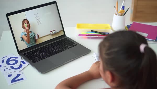 Teacher explains lesson material on laptop screen and little girl pupil ...