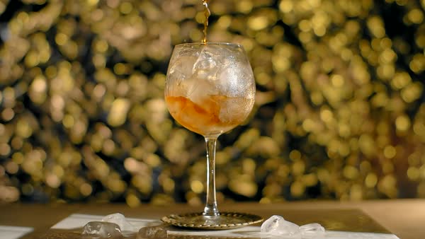 Cocktail is poured to the glass full of ice, ice cubes and sprinkling ...