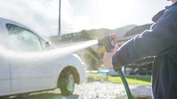 Kid spraying car with compressed water close up. Boy with water spray ...