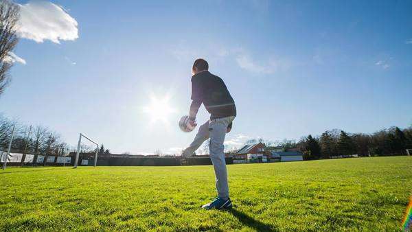Juggling soccer ball with sunshine in background. Young soccer player ...