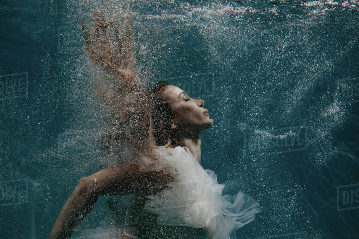 Portrait of beautiful swimming and diving woman in bridal dress ...
