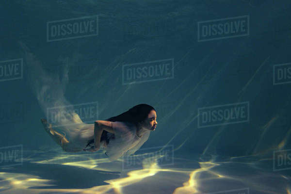 Underwater shoot of beautiful woman in white flying transparent dress ...
