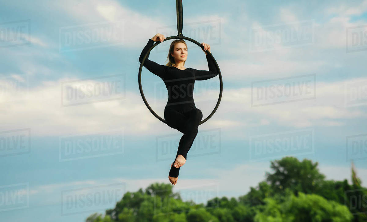 Woman aerialist performs acrobatic elements in hanging aerial hoop ...