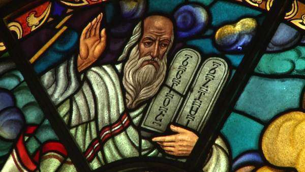 Medium shot of stained glass window in church depicting Moses and the ...