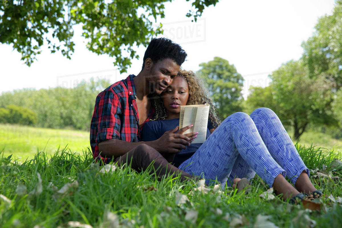 Couple cuddling and reading a book in a park - Royalty-free Stock Photo ...