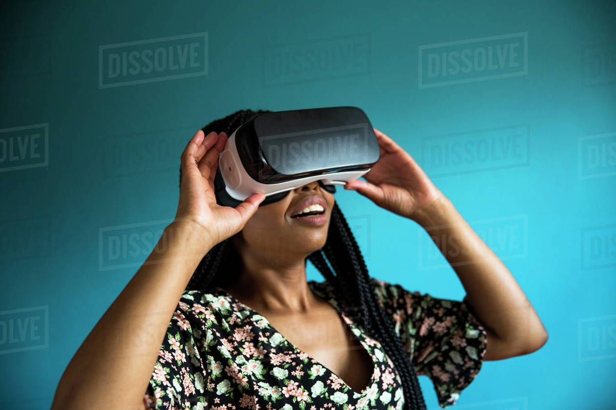 African woman looking through VR headset - Stock Photo - Dissolve