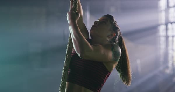 Attractive Muscular Female Bodybuilder Doing Rope Climbing Indoors ...