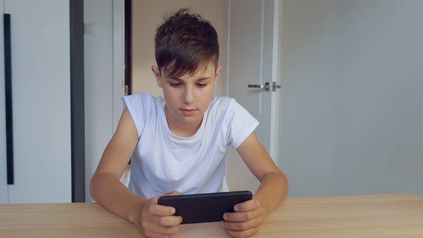 Boy playing mobile game on smartphone at home. Preschooler playing ...