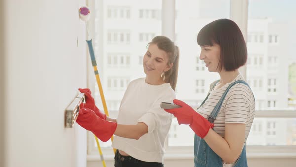 Two girls make repairs at home on their own. Close-up two women mark ...