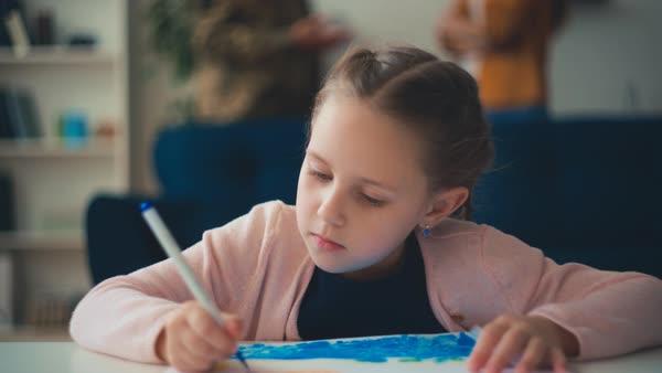 Little girl doing school homework, parents having fight in background ...