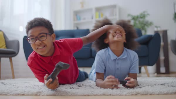 Two happy african american kids playing video game with joysticks, home ...