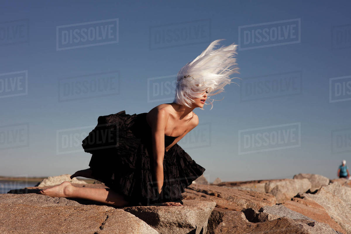 Woman kneeling on rocks - Stock Photo - Dissolve