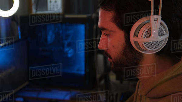 Male gaming on a pc streaming over the shoulder white headphones blue ...