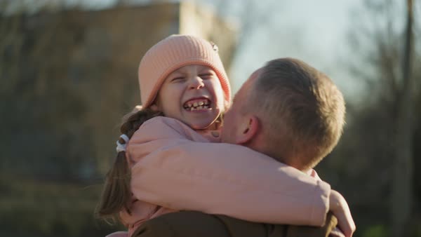 Joyful Hug: Little Girl in Pink Cap and Jacket Smiles Brightly While ...