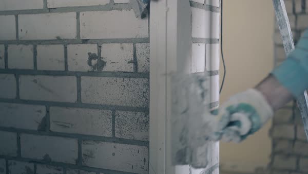 Skilled man hand fixes gypsum plasterboard lines on brick wall smearing ...