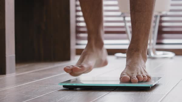 Close-up male legs stand on electronic automatic scales weight control ...