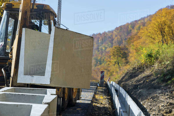 Concrete drain reconstruction workers installing precast square U-shape ...