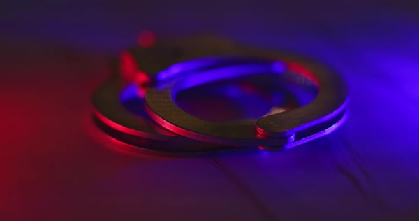 Police at under arrest of handcuffs police with the flashing red and ...