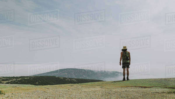 Man with camera looks out over mountains - Stock Photo - Dissolve