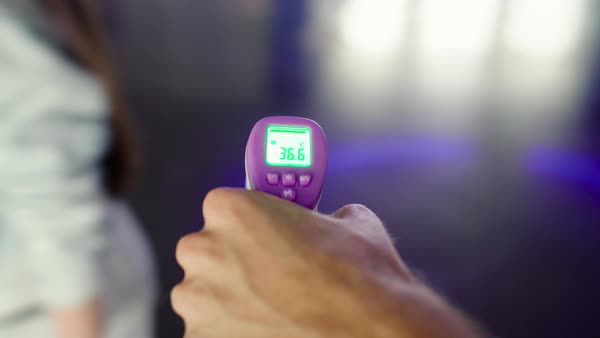 Close up of male hand measuring temperature of several people with non ...