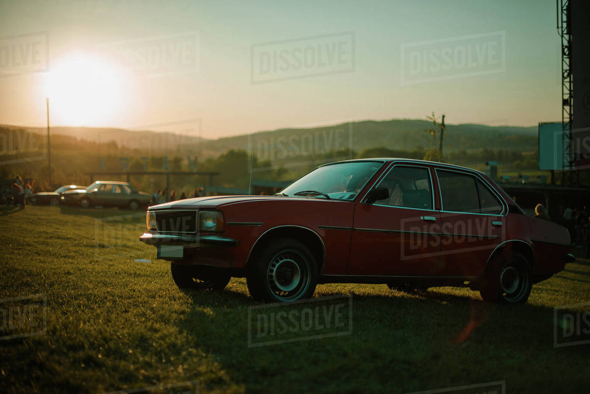 Vintage red car on grass at sunset - Royalty-free Stock Photo | Dissolve