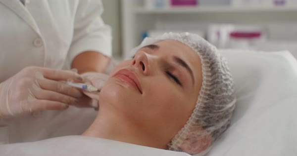 Close-up of the face of a female patient during the injection of plasma ...