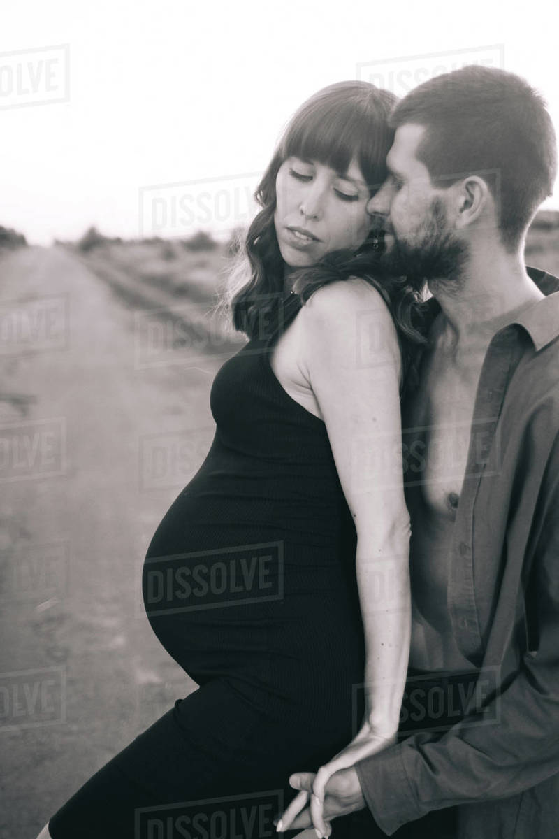A married couple who are expecting a baby are photographed at sunset in ...