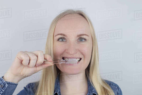 Close-up of a girl brushing teeth and look in front of a mirror. Oral ...