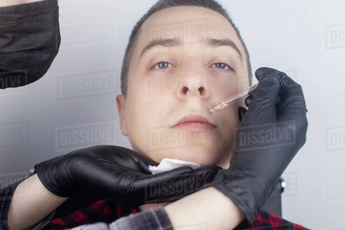 Beard growth. The master in the barber shop applies a special oil to ...