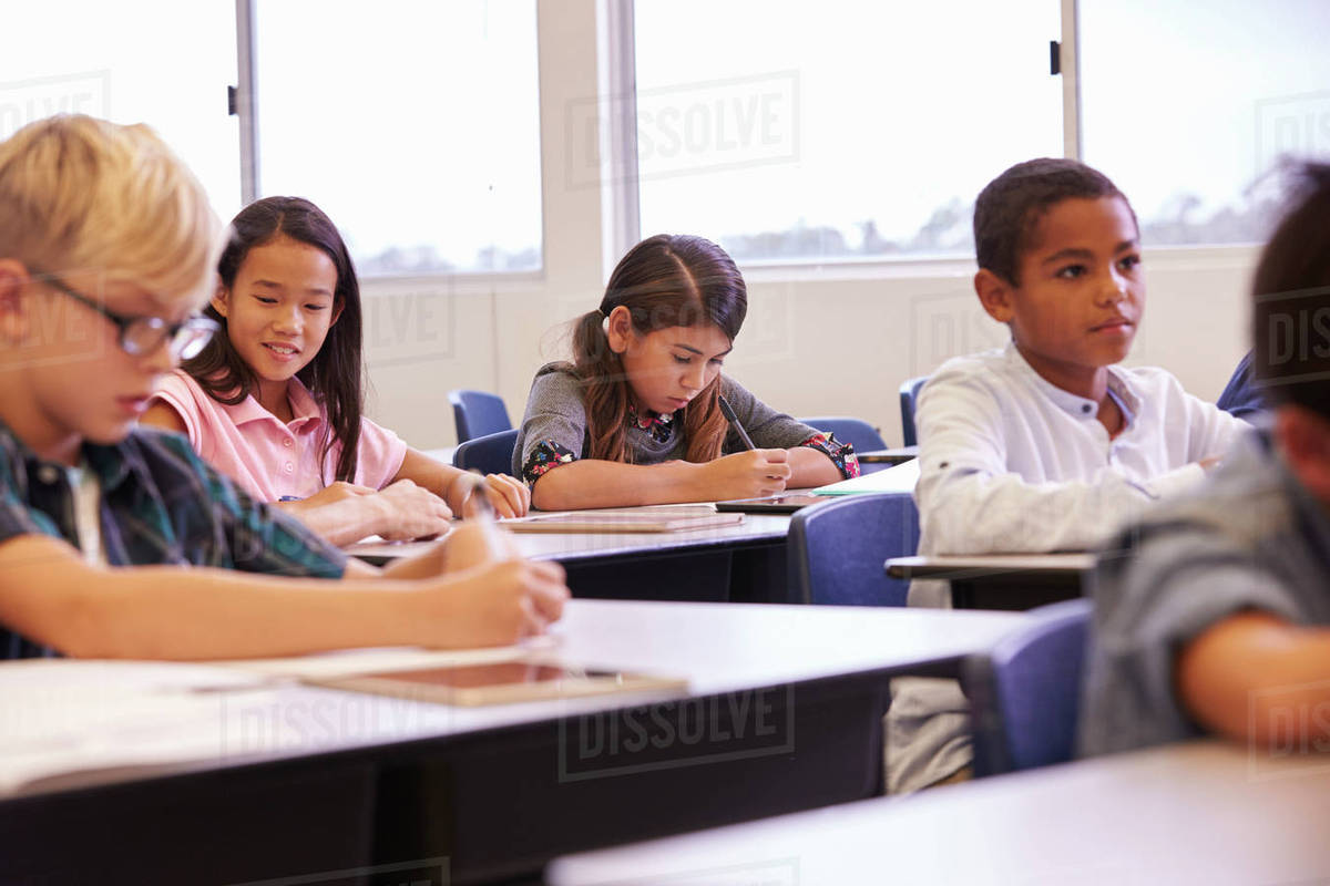 Elementary school kids working at their desks in a classroom - Royalty ...