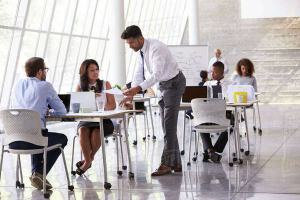 Manager helping staff in busy office environment - Royalty-free Stock ...